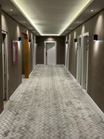 Corredor com pisos cobertos de carpete, paredes de madeira e portas numeradas 703, 706 e 707.