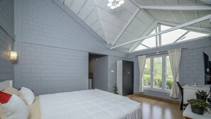 Quarto com cama grande, escrivaninha e janela com cortinas.