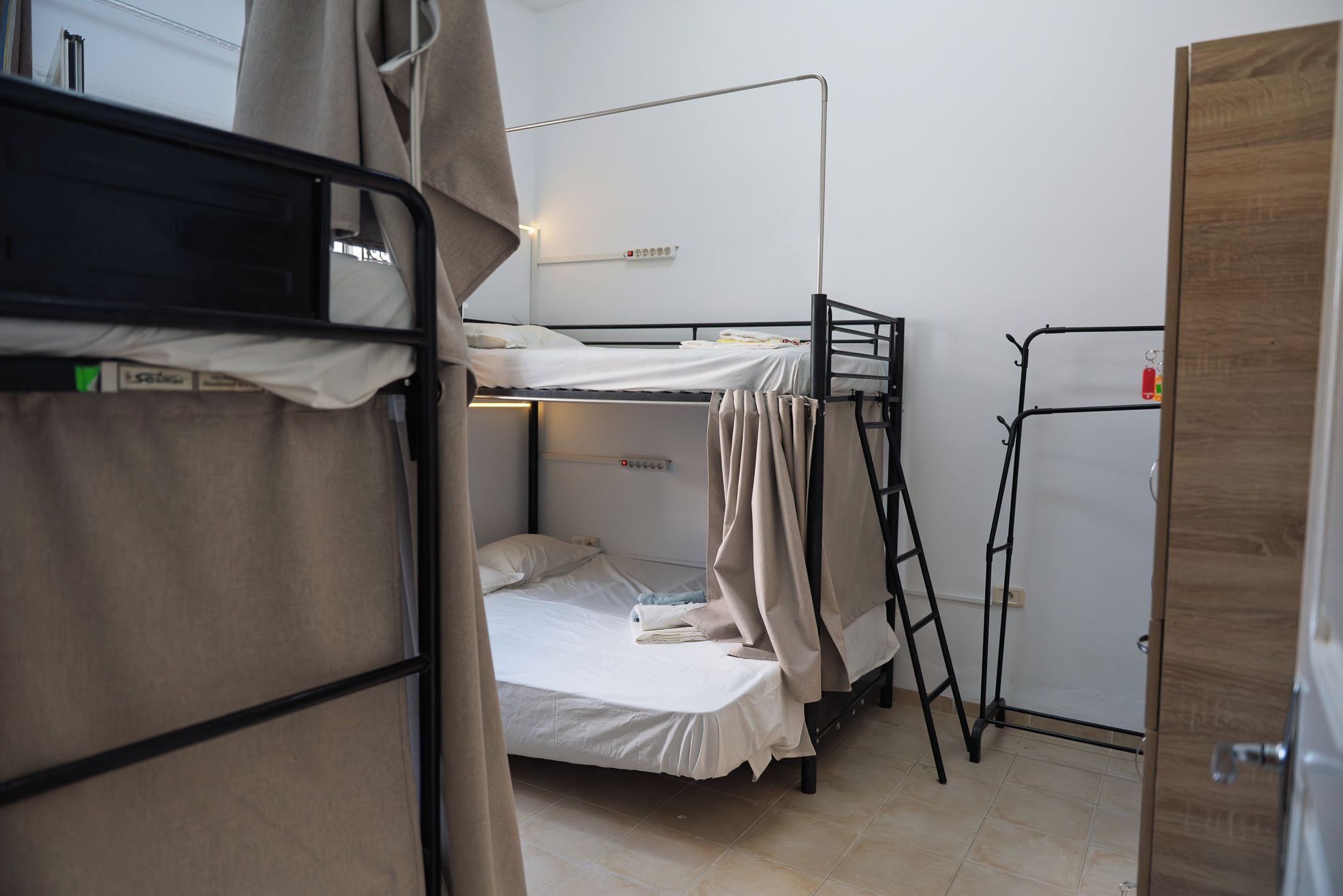 Quarto em dormitório com beliches, escrivaninha e escada.