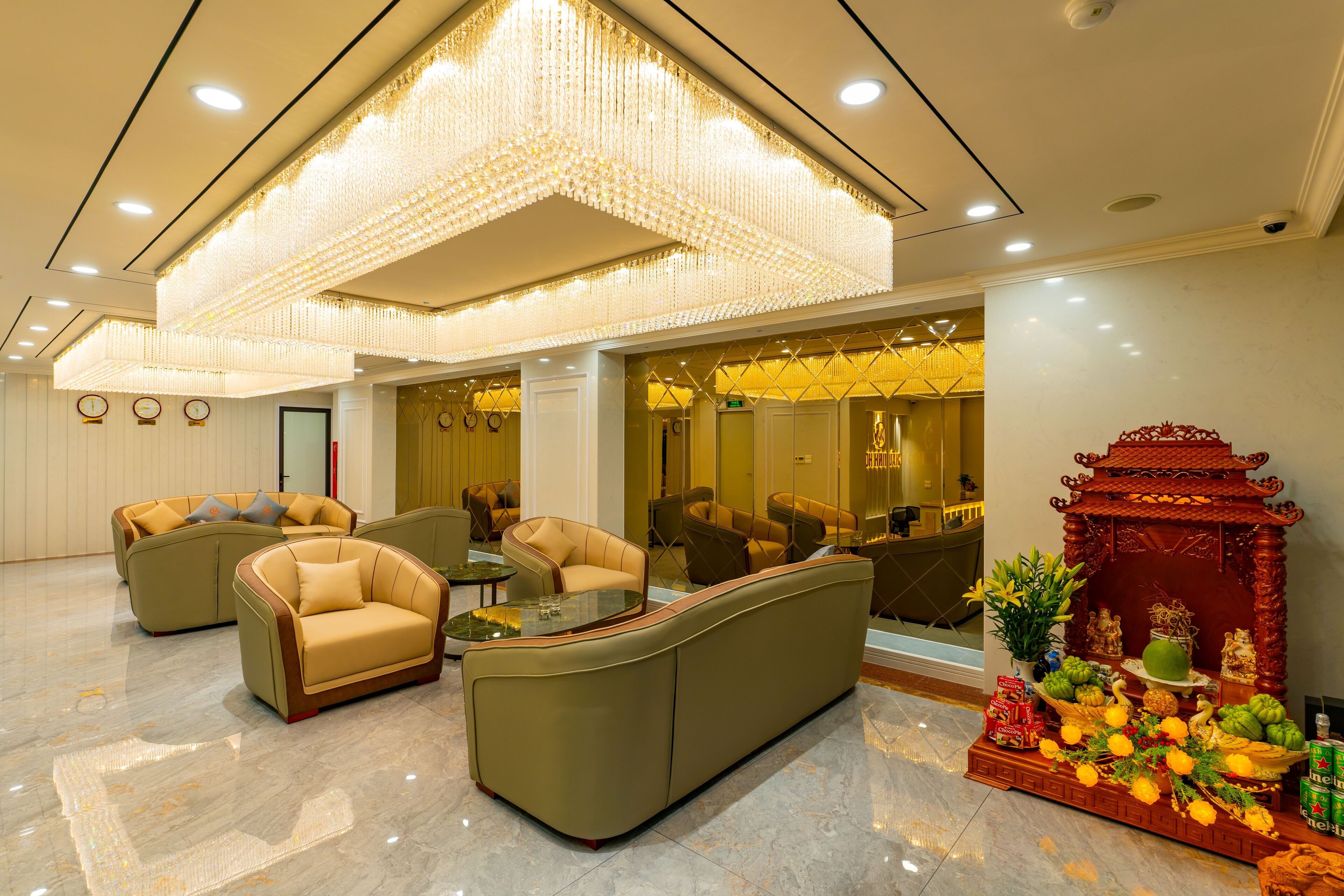 Um lobby moderno com sofás, uma mesa de centro de vidro, um altar decorativo e um grande candelabro.
