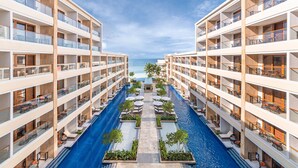 Um hotel com vários andares, piscina central, varandas em cada andar e vista para o oceano.
