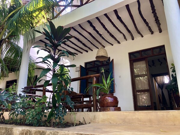 Um edifício com fachada rústica, vigas de madeira e um vaso grande com planta em primeiro plano.