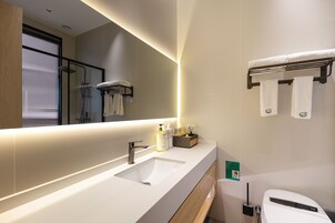Uma casa de banho moderna com um espelho grande, lavatório e porta-toalhas.
