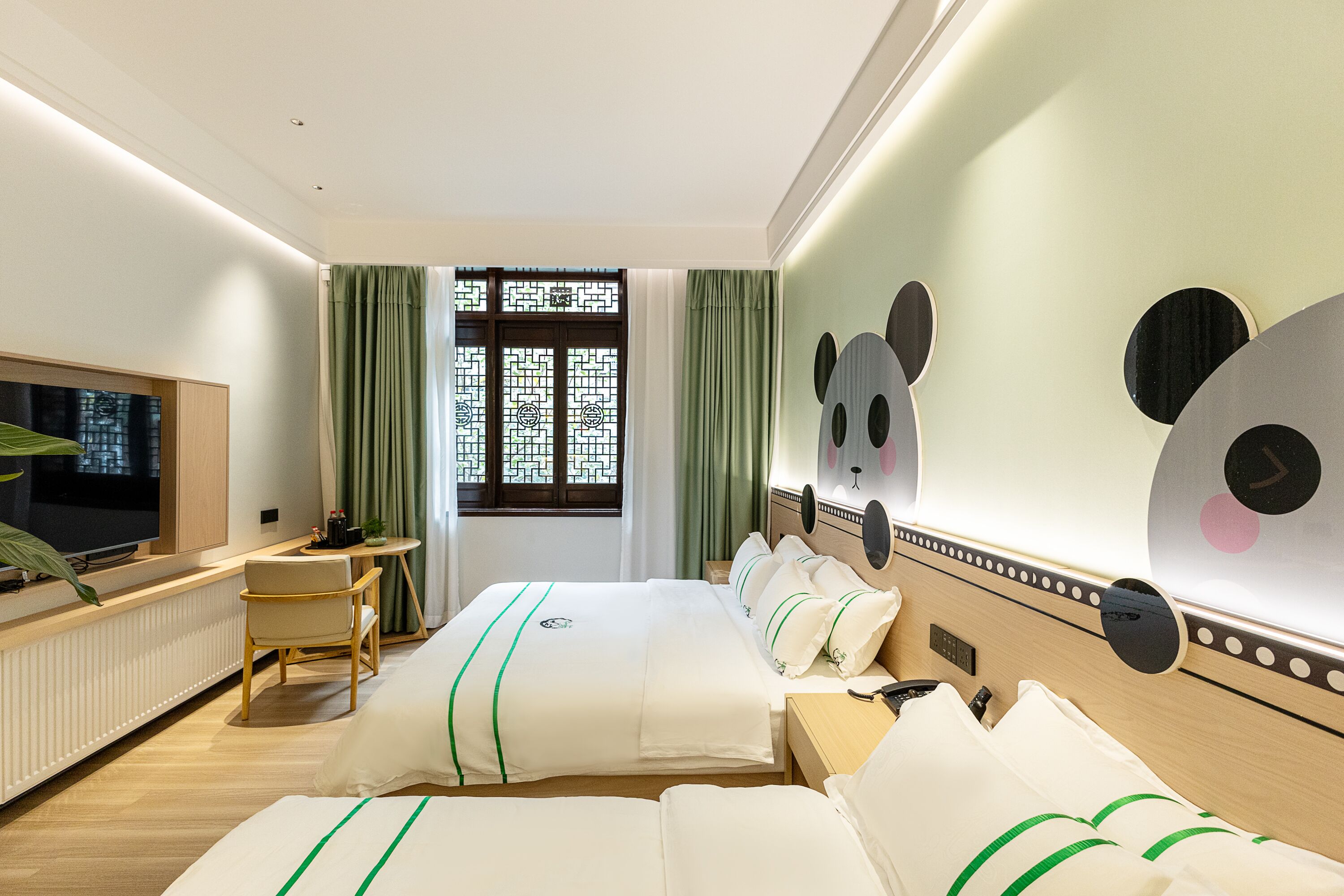 Quarto de hotel com duas camas, televisão, escrivaninha e janela com cortinas.