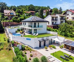 Uma casa moderna de dois andares com piscina, varanda coberta e um jardim bem cuidado.