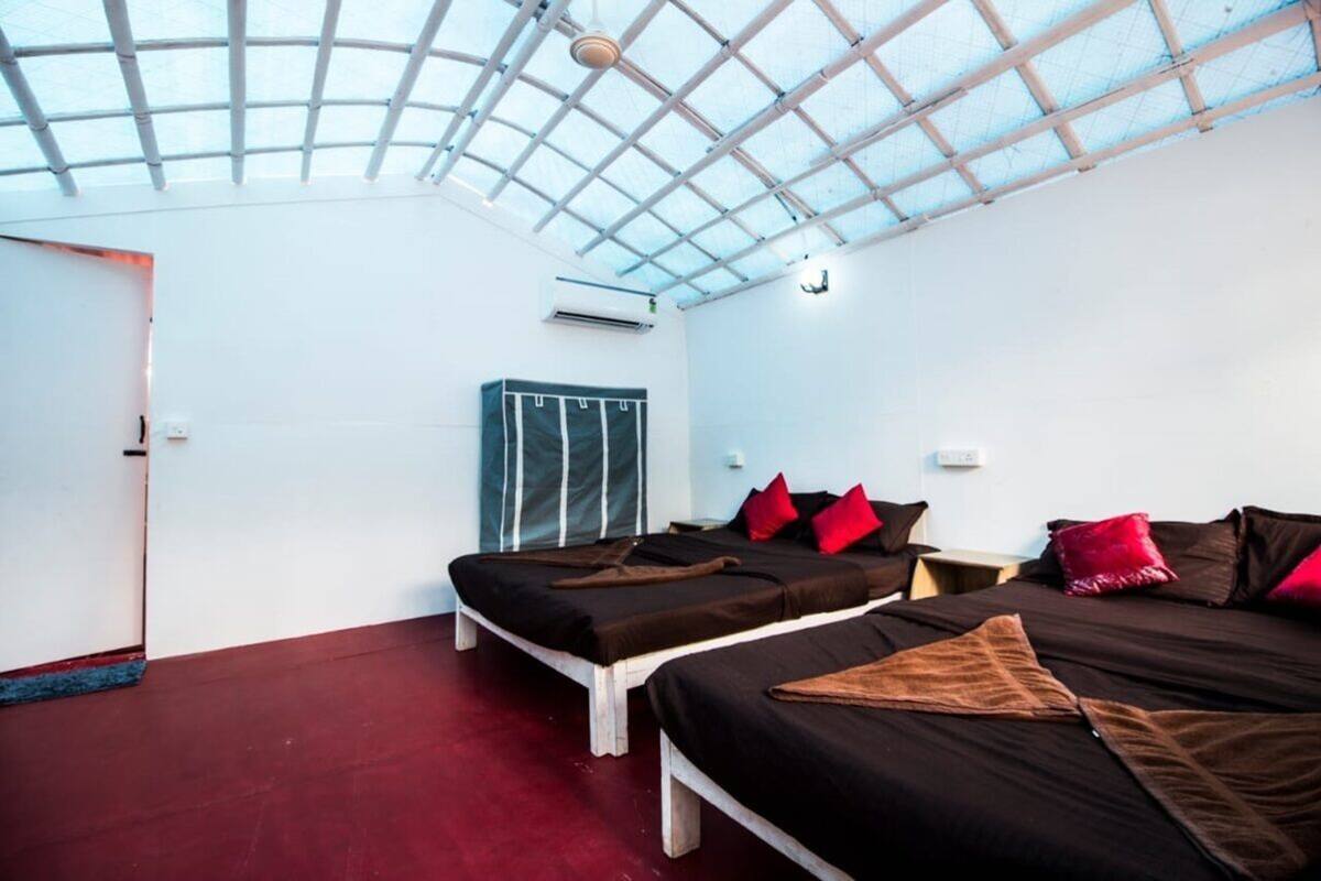 Quarto com duas camas, claraboia e piso vermelho.