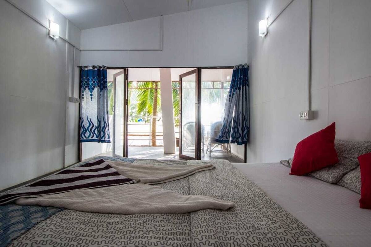 Quarto com cama, janela com cortinas e vista para o exterior.