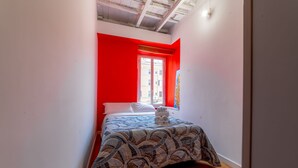 Quarto com cama, janela com vista e parede de destaque vermelha.