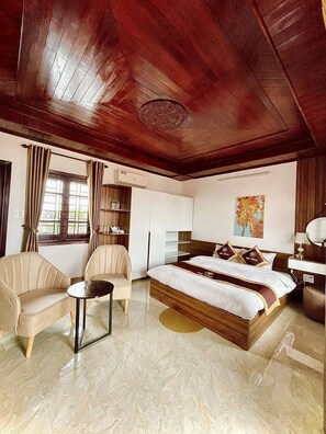 Um quarto espaçoso com uma cama grande, um sofá, uma mesinha e uma escrivaninha.