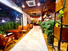 Um espaço interno moderno com mobiliário de madeira, plantas em vasos e uma área de recepção.