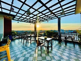 Terraço no telhado com piso xadrez, mesas, cadeiras e luminárias pendentes.