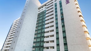 Um edifício alto e moderno com uma placa de destaque 'Mercure' na lateral.