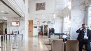 Um hall amplo com pisos e paredes de mármore, um balcão de recepção e áreas de estar.