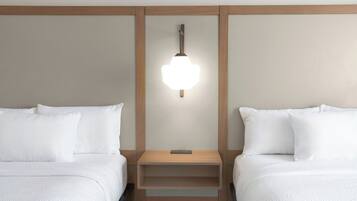 Quarto de hotel com duas camas, uma mesa de cabeceira, uma luminária na parede e painéis de madeira.