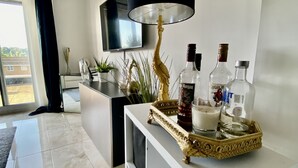 Uma sala de estar moderna com um console branco, uma luminária preta e garrafas decorativas.