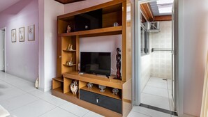 Sala de estar com um rack de madeira, televisão e objetos decorativos.