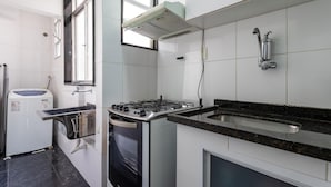 Uma cozinha moderna com fogão a gás, forno embutido e uma pia de aço inoxidável.