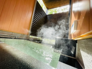 Uma área de águas termais com piscina e vapor subindo da água.