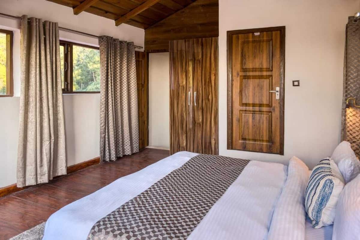 Quarto com cama grande, guarda-roupa de madeira e cortinas.
