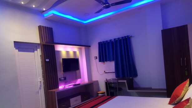 Quarto moderno com cama, televisão e área de trabalho.