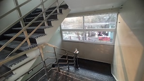Escada com grades de metal e janela com vista para área externa.