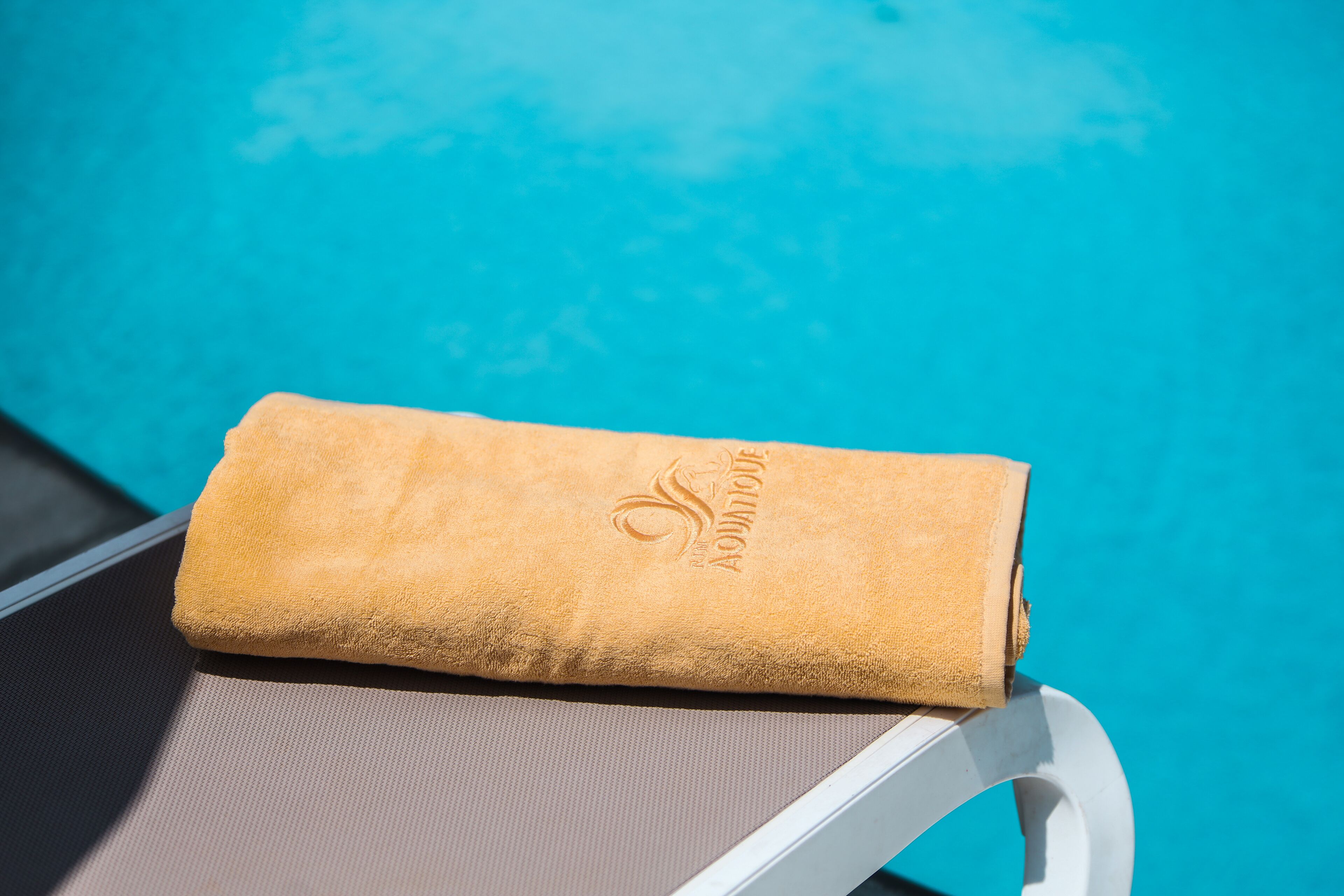 Uma toalha com um logotipo numa cadeira perto de uma piscina.