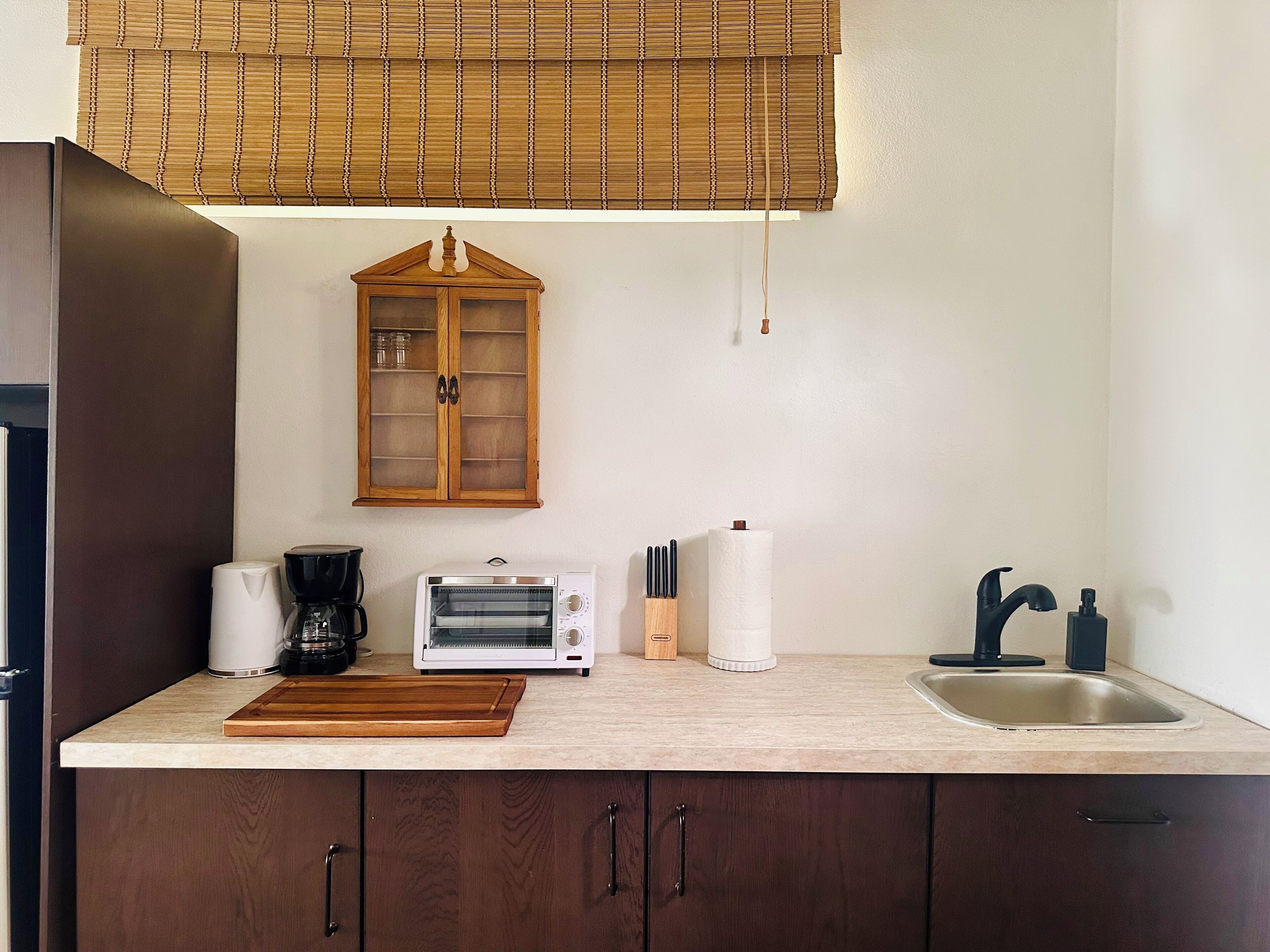 Uma cozinha com armário de madeira, cafeteira, torradeira e pia.