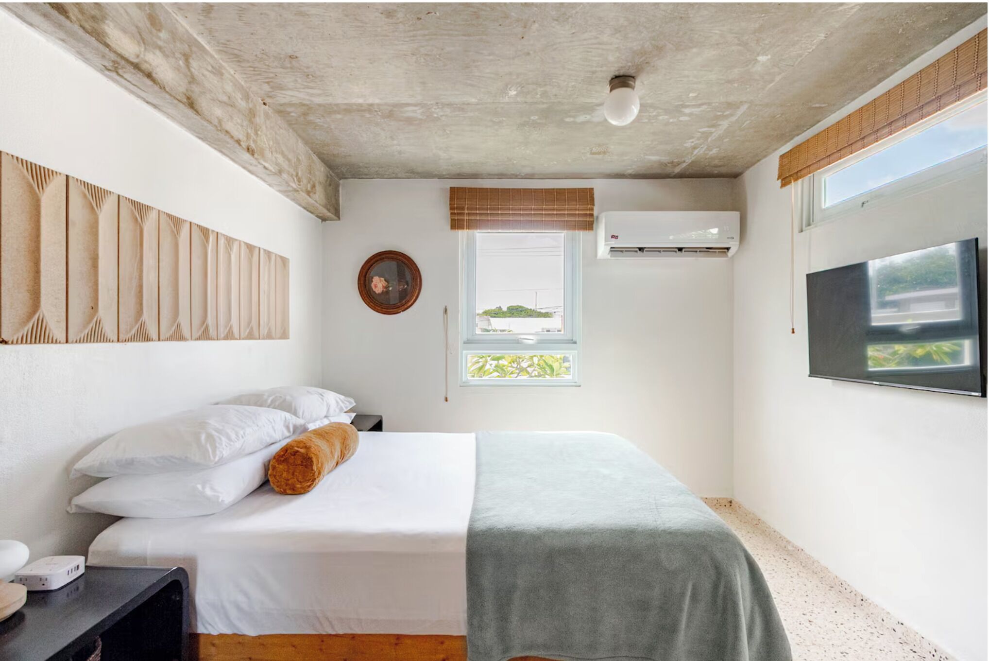 Quarto com cama, janela, ar condicionado e televisão.