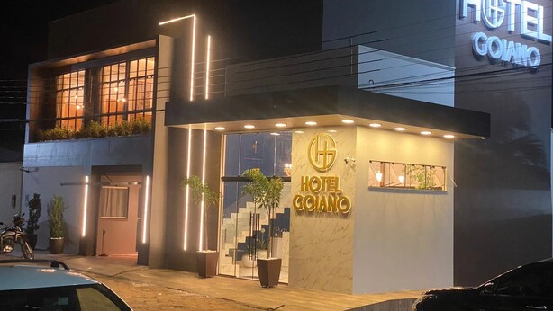 Um hotel moderno com uma placa de destaque, uma escadaria e um carro estacionado na frente.