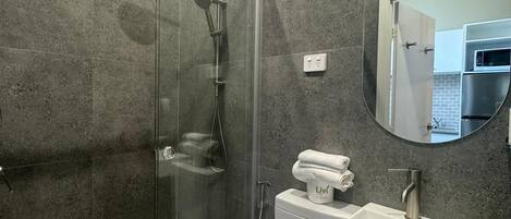 Um banheiro moderno com chuveiro envidraçado, vaso sanitário branco e pia com espelho.