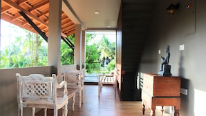 Quarto com piso de madeira, móveis brancos e vista para o verde lá fora.