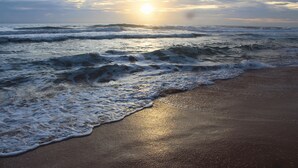 Uma praia com ondas e um pôr do sol.