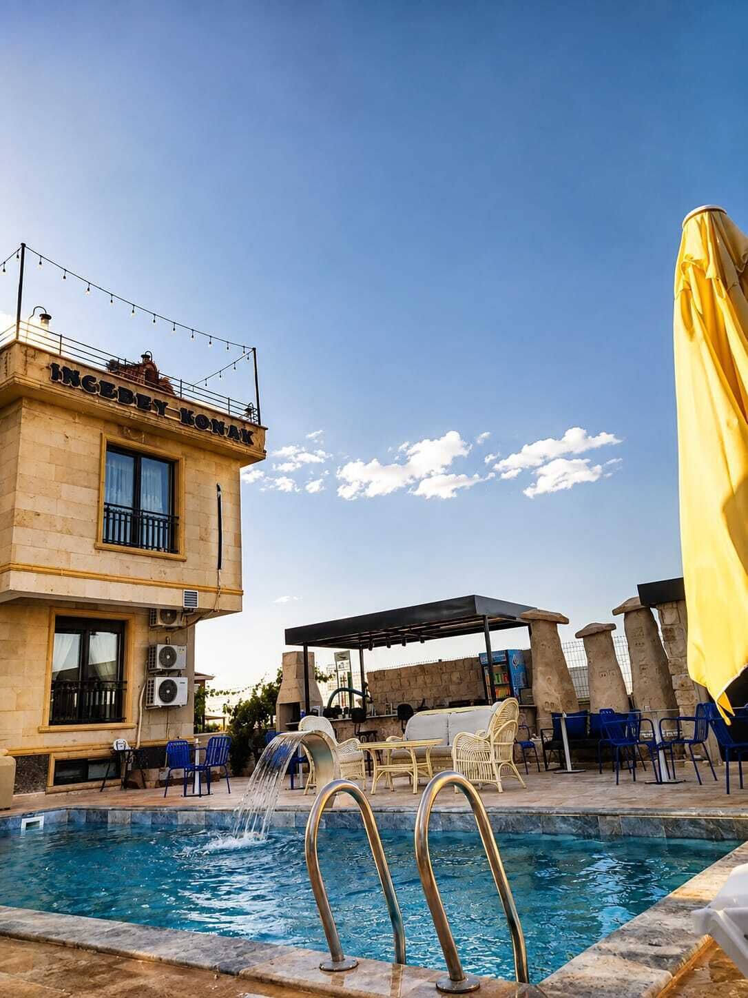 Piscina com recurso de água, área de estar ao ar livre e um edifício com aparelhos de ar condicionado.