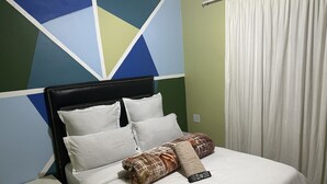 Cama bem arrumada com lençóis brancos, cabeceira e manta.
