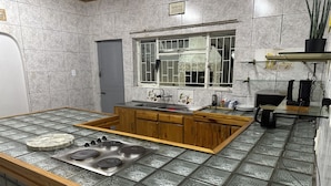 Uma cozinha com ilha central, armários de madeira, pia e janela com azulejos decorativos.