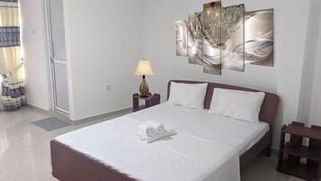 Quarto de hotel com uma cama grande, uma mesa de cabeceira com abajur e uma obra de arte na parede.