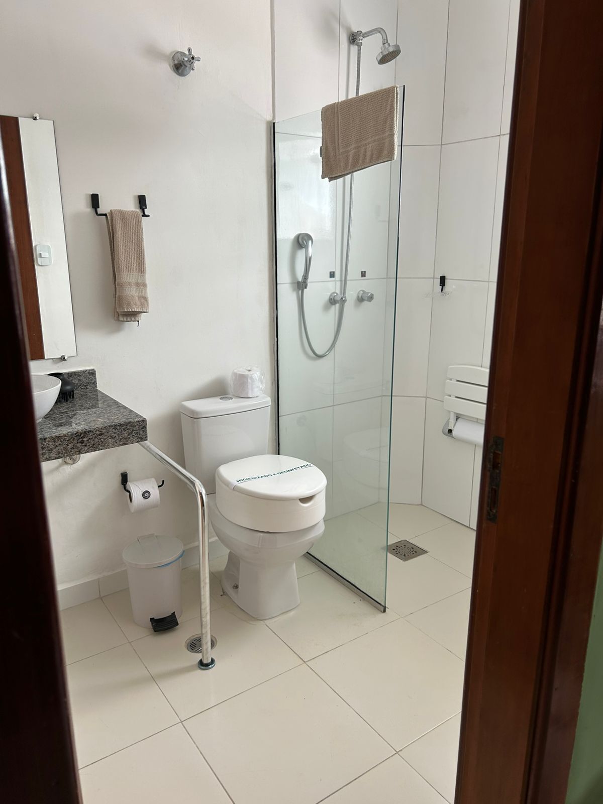 Uma casa de banho moderna com cabine de chuveiro em vidro, sanita, lavatório com bancada de mármore e espelho.