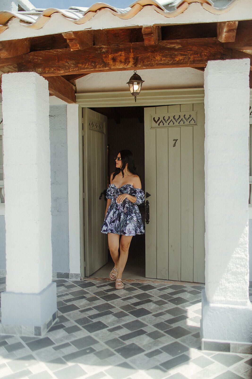 Uma pessoa saindo de um prédio com piso de azulejos e uma porta identificada com o número 7.