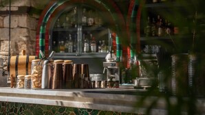 Uma área de bar com prateleiras de garrafas, uma máquina de café e diversos utensílios de bar.