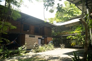 Um edifício com área externa coberta, rodeado por vegetação.