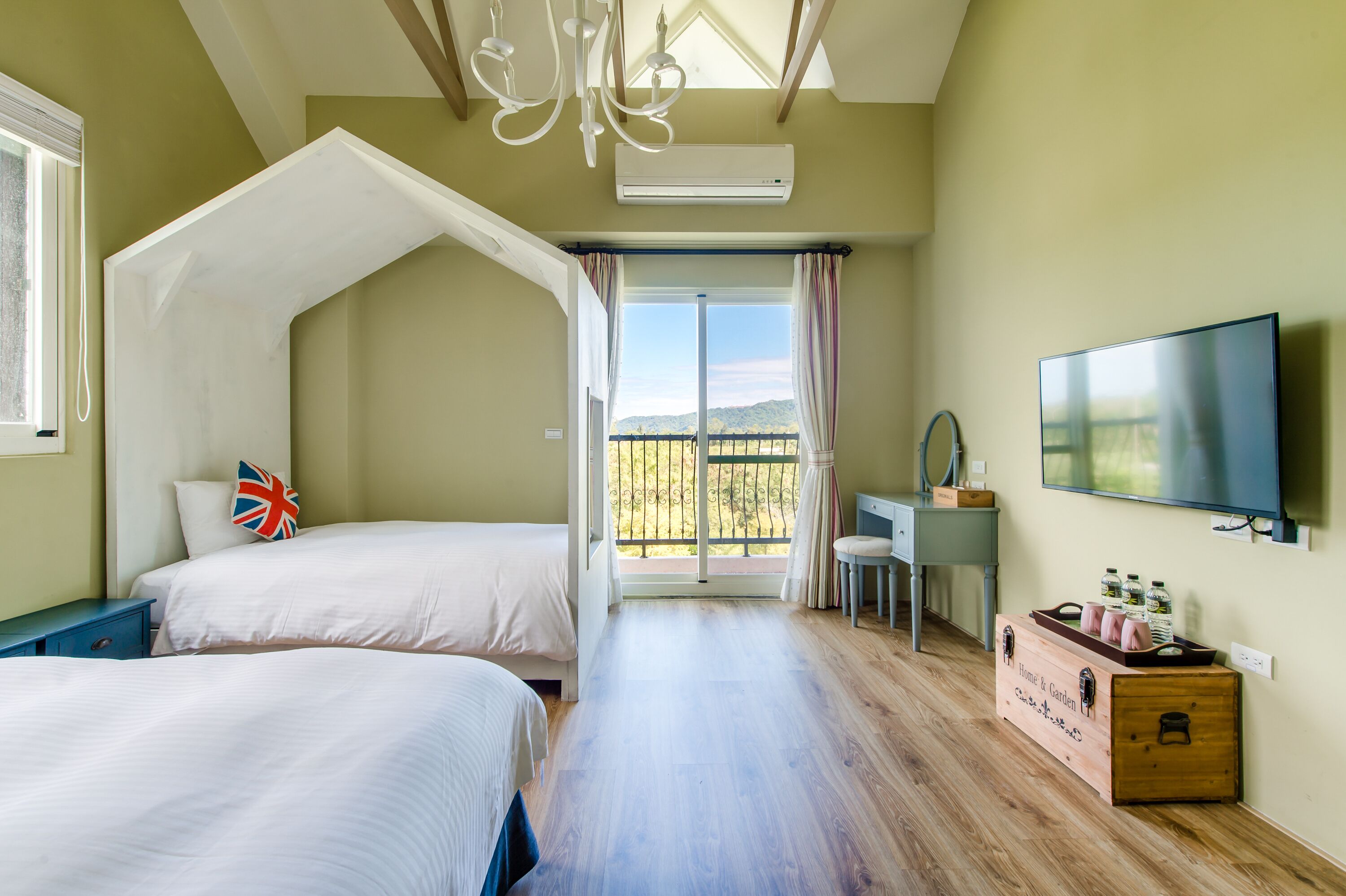 Quarto com duas camas, TV, escrivaninha e vista para o exterior.