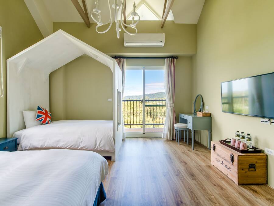 Quarto com duas camas, TV, escrivaninha e vista para o exterior.