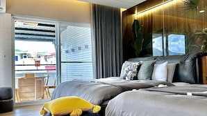 Quarto moderno com uma cama grande, um espaço de estar pequeno e vista para o exterior.
