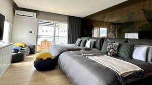 Quarto moderno com uma cama grande, um espaço de estar pequeno e vista para o exterior.