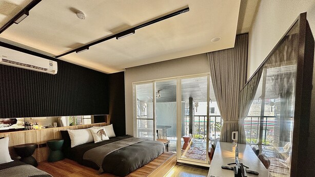 Quarto moderno com uma cama grande, uma escrivaninha e uma varanda com vista para a cidade.