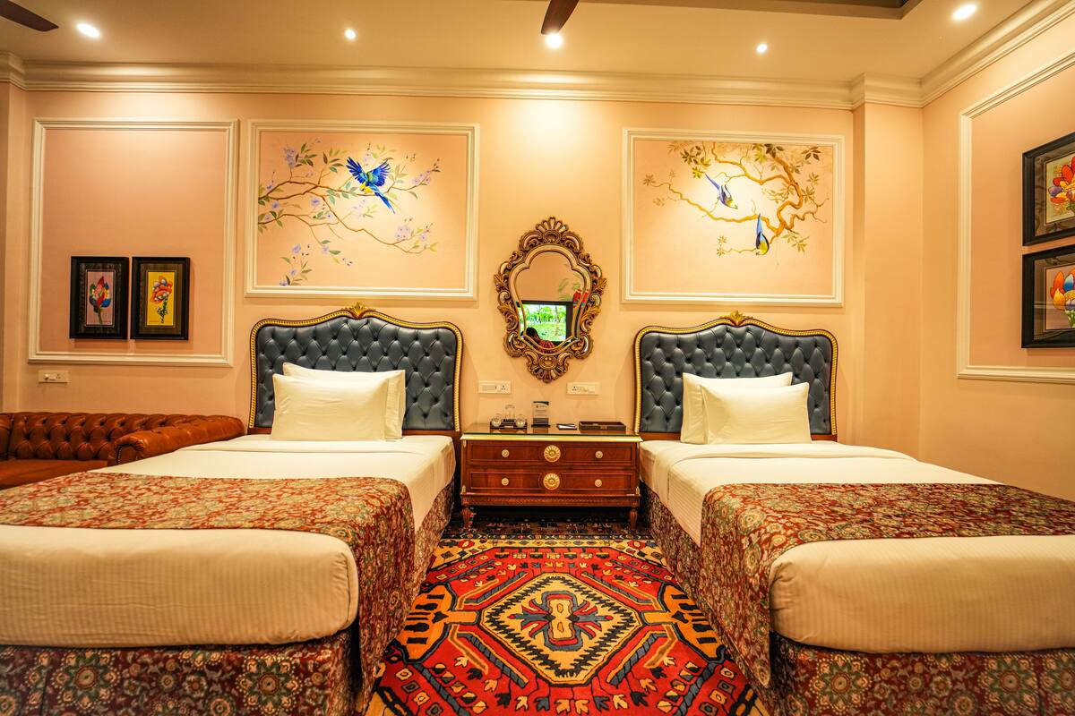 Quarto de hotel com duas camas, um espelho grande e obras de arte nas paredes.
