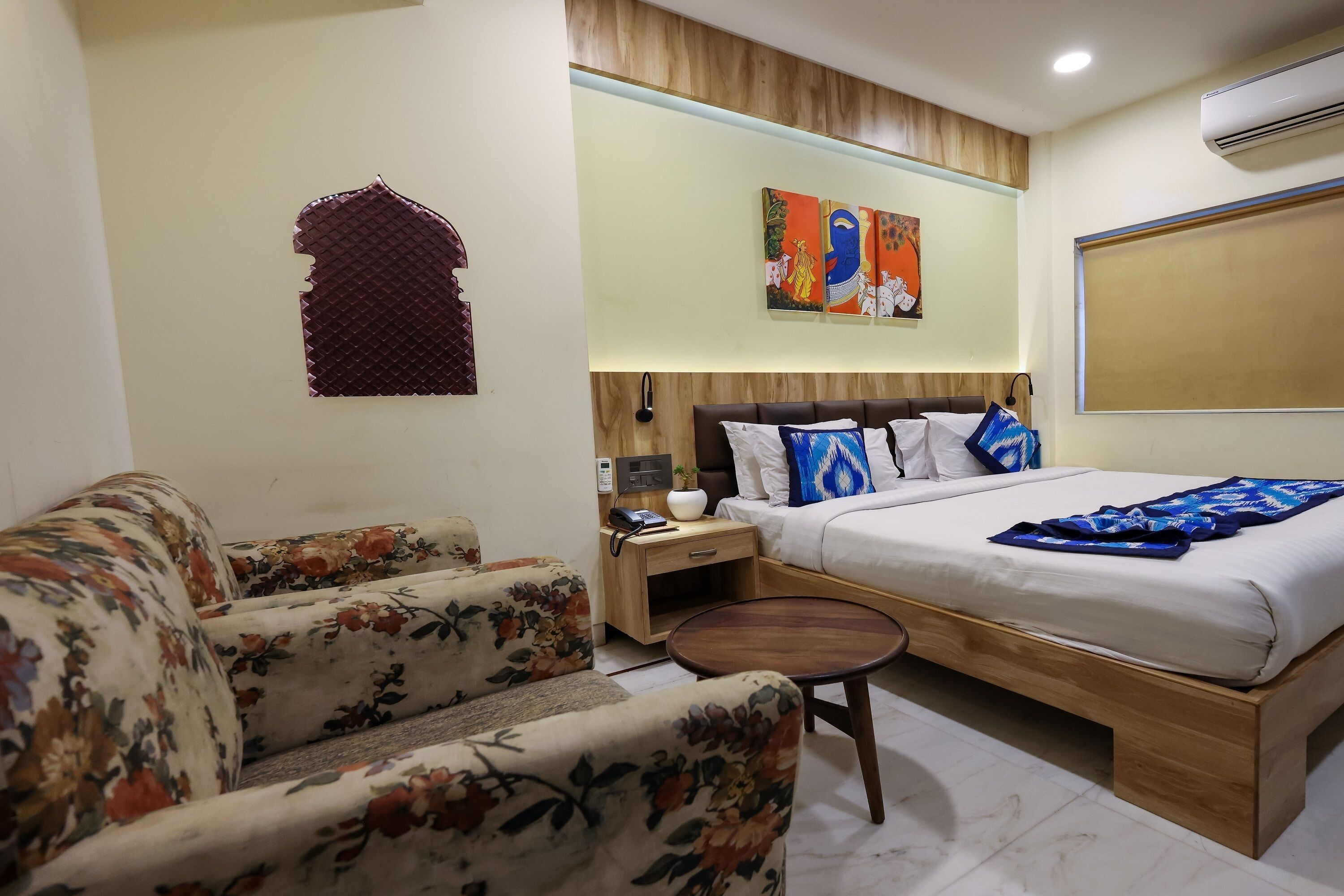 Quarto de hotel com cama, sofá, mesa de cabeceira e uma pequena mesa.