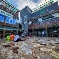 Um pátio com piso de mosaico, área de bar e um edifício com a placa "696 ARENA".