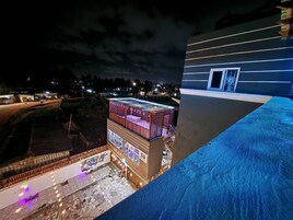Um edifício moderno com telhado plano, grandes janelas e uma área de varanda com iluminação externa.