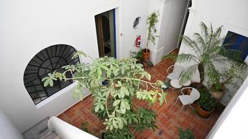 Pátio com escadaria, plantas em vasos e uma cadeira branca.